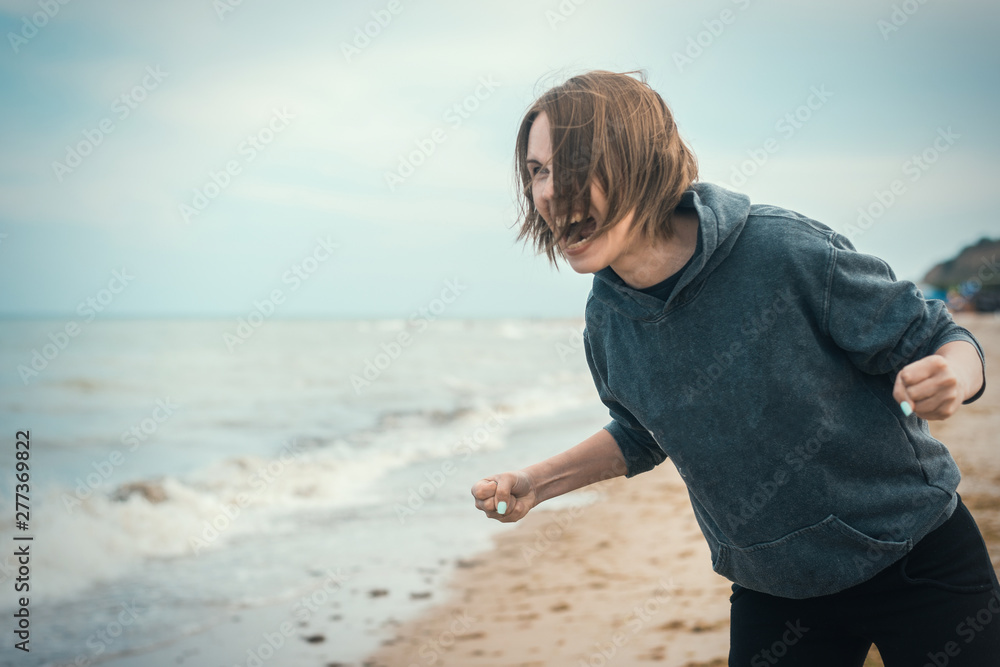 An angry, frantic woman shouts negative emotions on the sea, the ocean ...