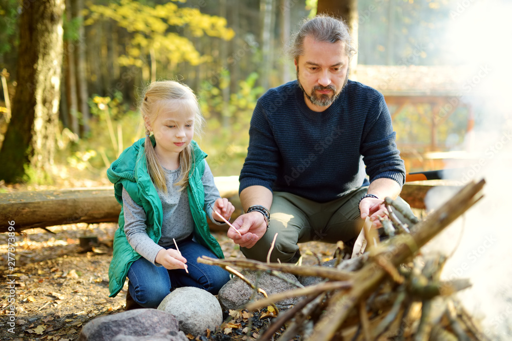 Cute young girl learning to start a bonfire. Father teaching her ...
