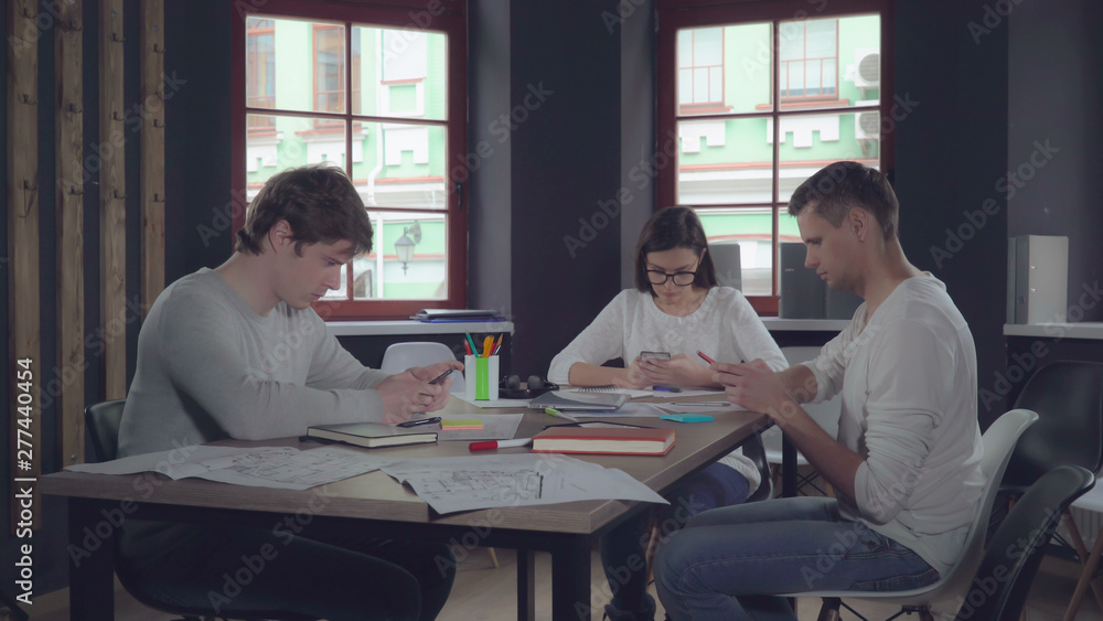 group of people sitting at the desk using gadgets in the casual ...