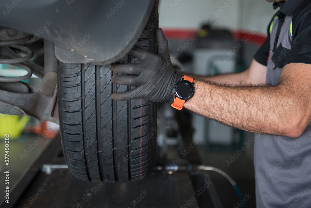 car mechanic placing the rear wheel in place Stock Photo | Adobe Stock