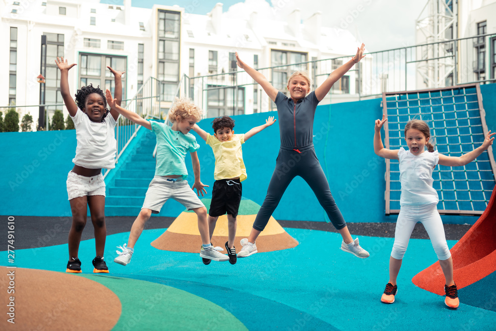 Cheerful pupils jumping up and down on a sports ground. Stock Photo ...