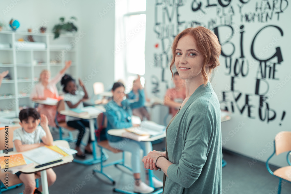 Beautiful teacher standing in front of her class. Photos | Adobe Stock