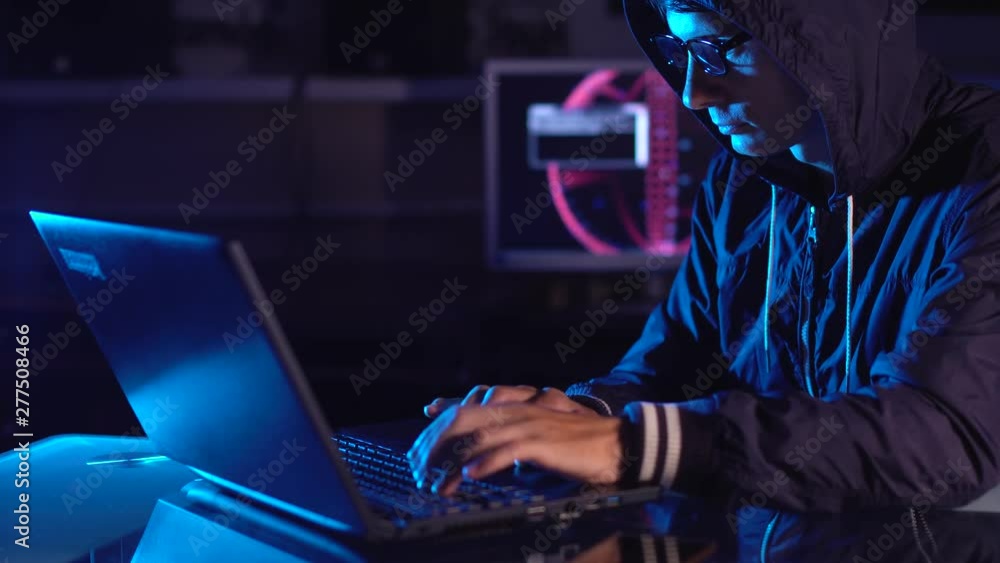 Hacker typing program code while committing a cybercrime hacking a ...