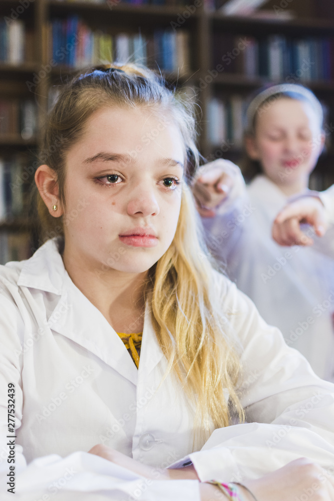 Little bullied girl crying in library Stock Photo | Adobe Stock