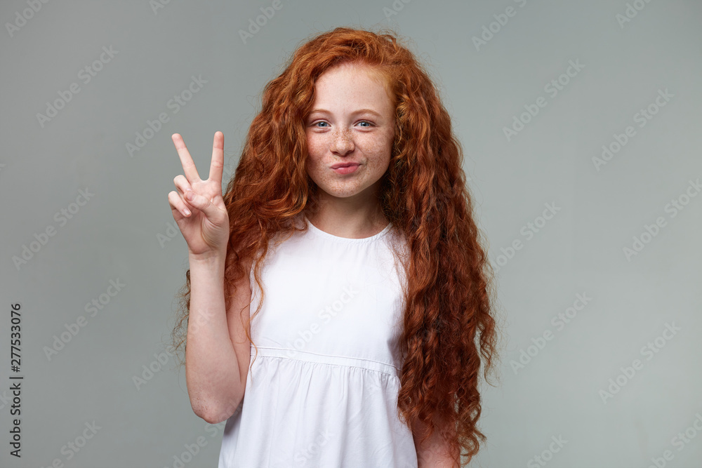 Camera shot of funny little girl with ginger hair and freckles, shows ...