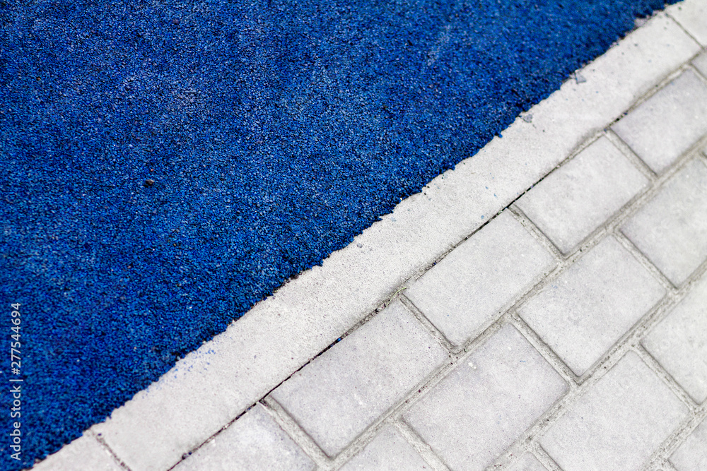 bright blue asphalt bordered on a gray brick road; photo shows the ...