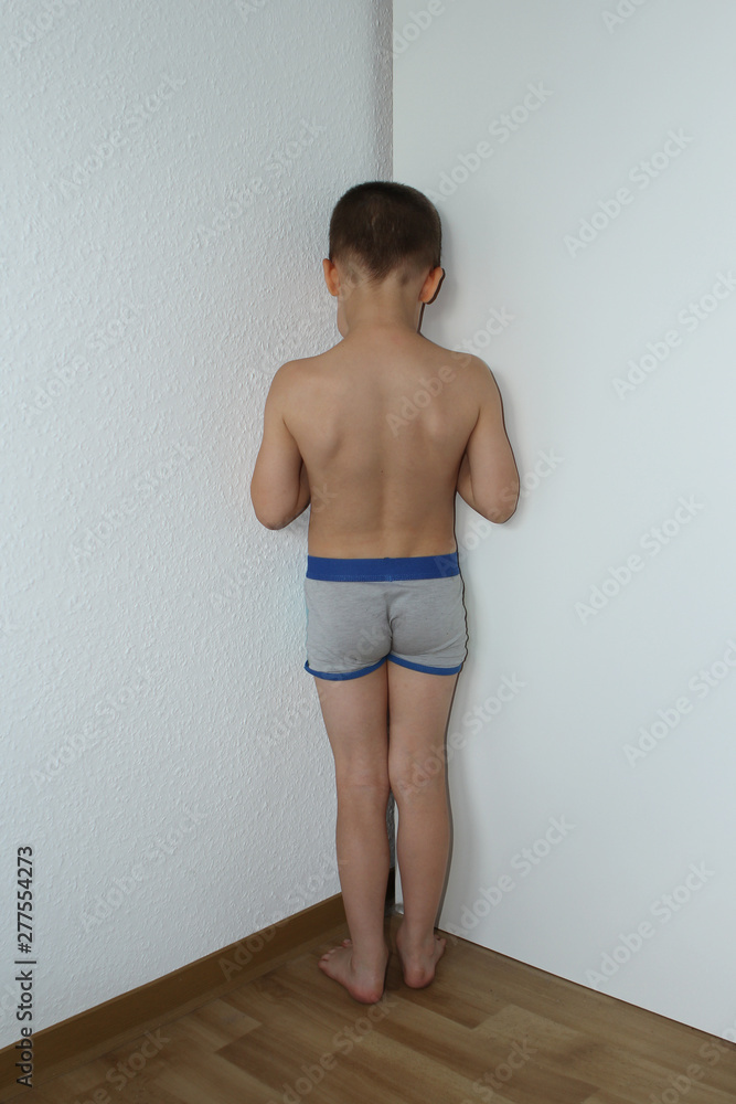 Boy Junior Schoolboy Standing In The Corner Undressed Facing The
