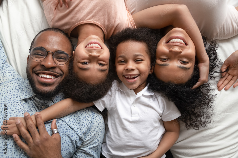 Happy african family lying on bed cuddling, portrait, top view Stock ...