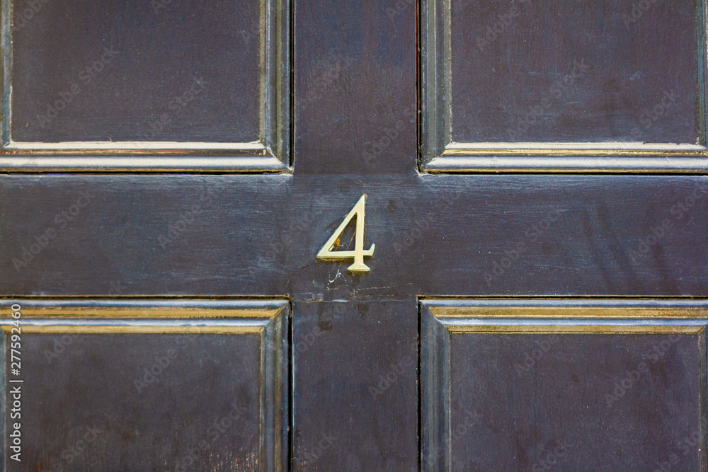 House number four with the 4 in bronze on a black wooden front door ...