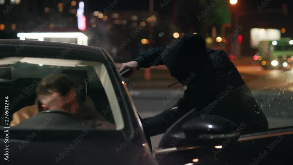 Close up gangster with gun attacked a man in a car at night street ...