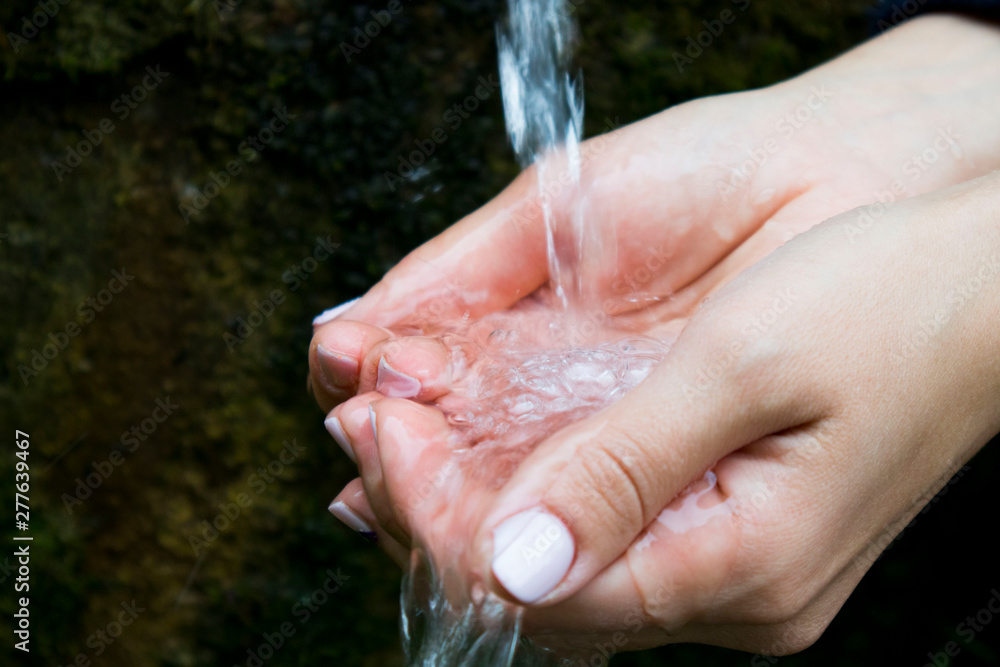 water flows into women's hands, hands with splashes of water, pure ...