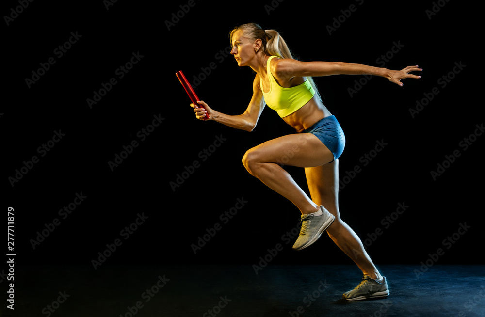 Professional female relay racer training isolated on black studio ...
