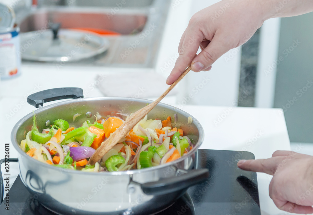 Chef preparing cook vegetables frying on pan with a lot of white smoke ...