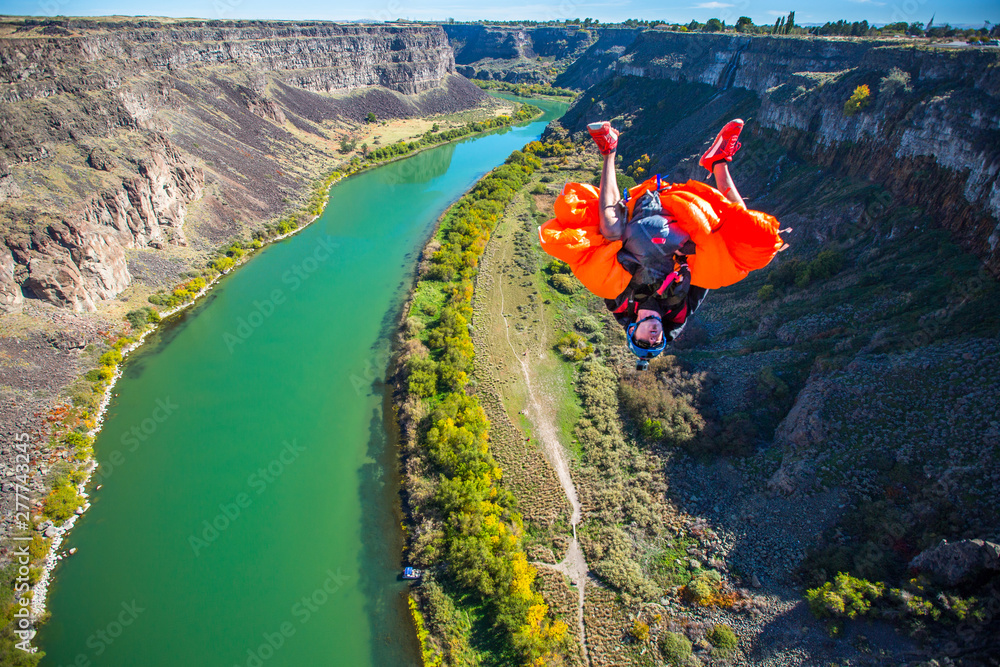 Man BASE jumping in canyon Stock Photo | Adobe Stock