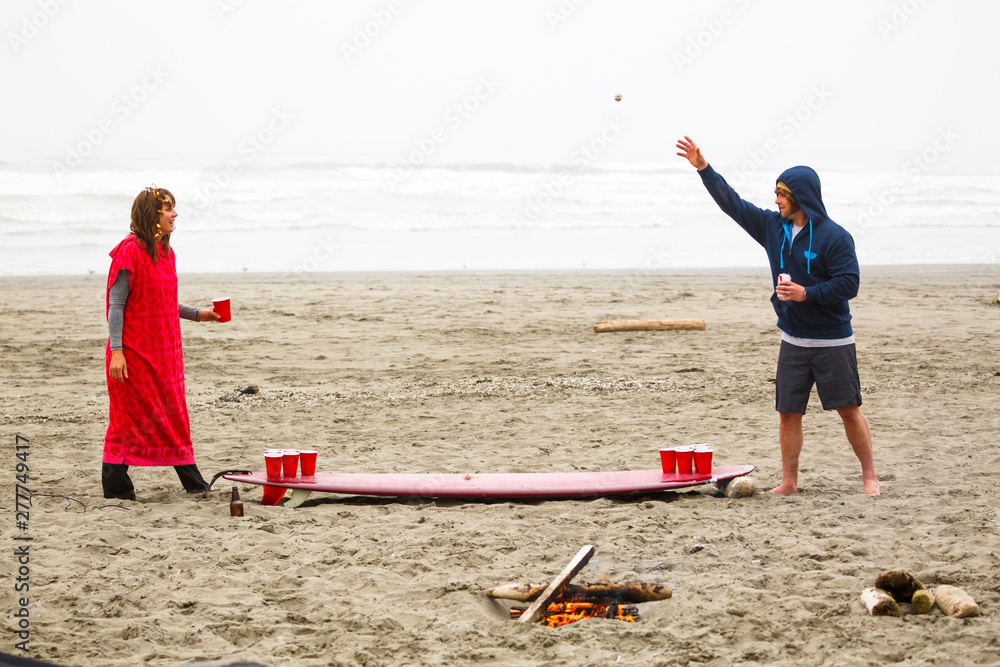 A man and woman play surfboard beer pong on a beach near Kalaloch ...