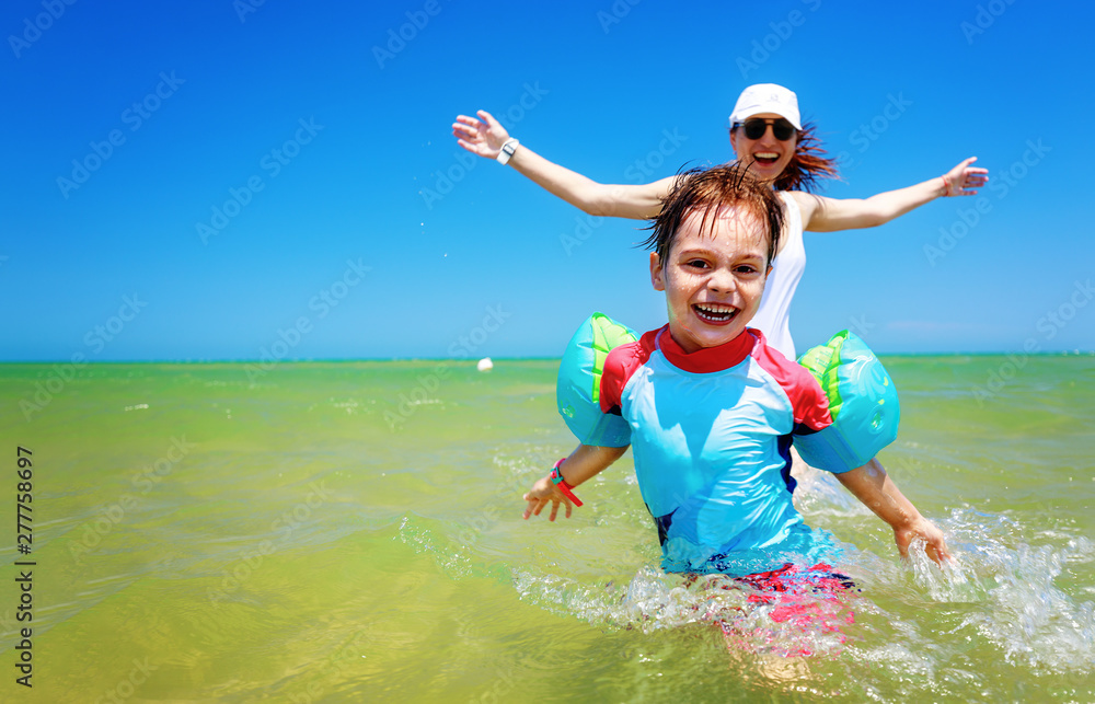 Excited kid playing in water on the beach in summer - Mother and son ...