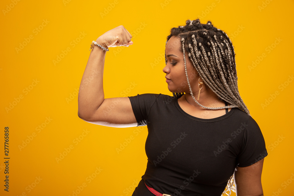 Young Afro American woman shown her arm muscles. Concept of fighting or ...