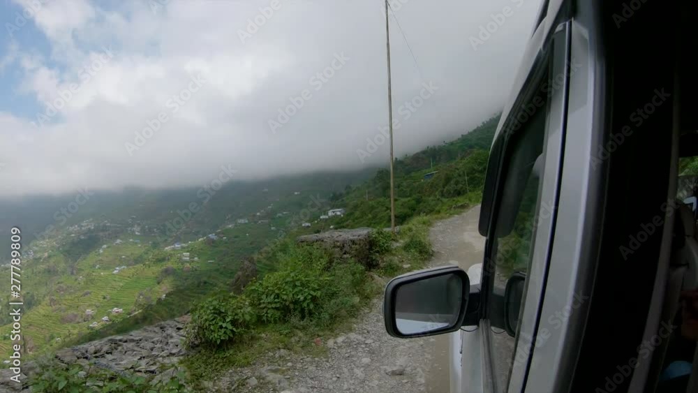 POV: Driving along the edge of scary bumpy road overlooking the forest ...
