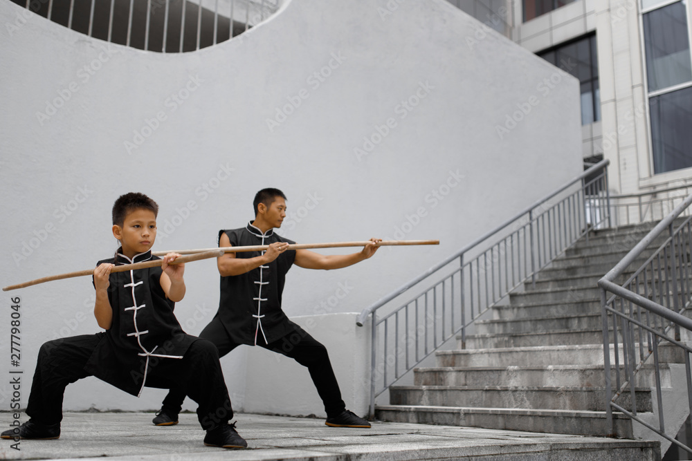 Son and father are engaged in Wushu. Morning Wushu training in the city ...