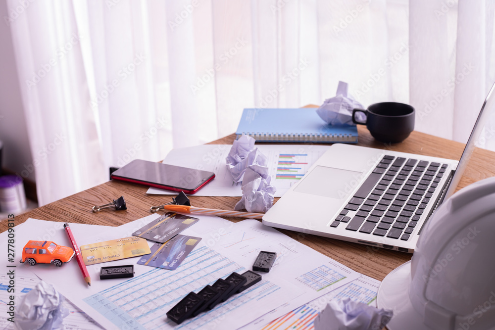 wood office table with laptop and paperwork, latte coffee cup, crumpled ...