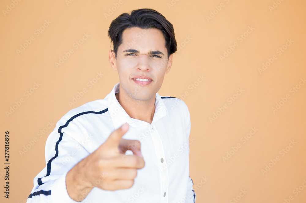 Frowning handsome guy pointing with forefinger at camera. Portrait of ...
