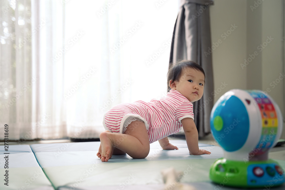 Foto de Asian cute scamp baby crawling on soft mat at home and turning ...