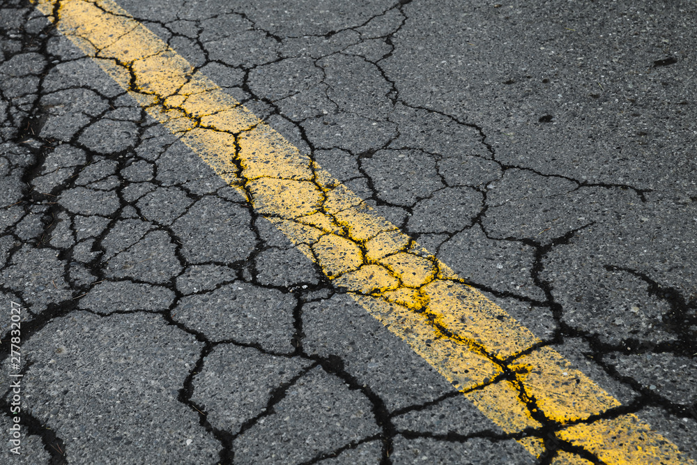 Cracked asphalt road with yellow dividing line Stock Photo | Adobe Stock