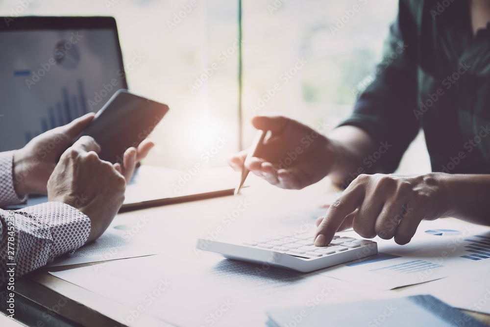 Business and partnership discussing using calculator to review balance ...