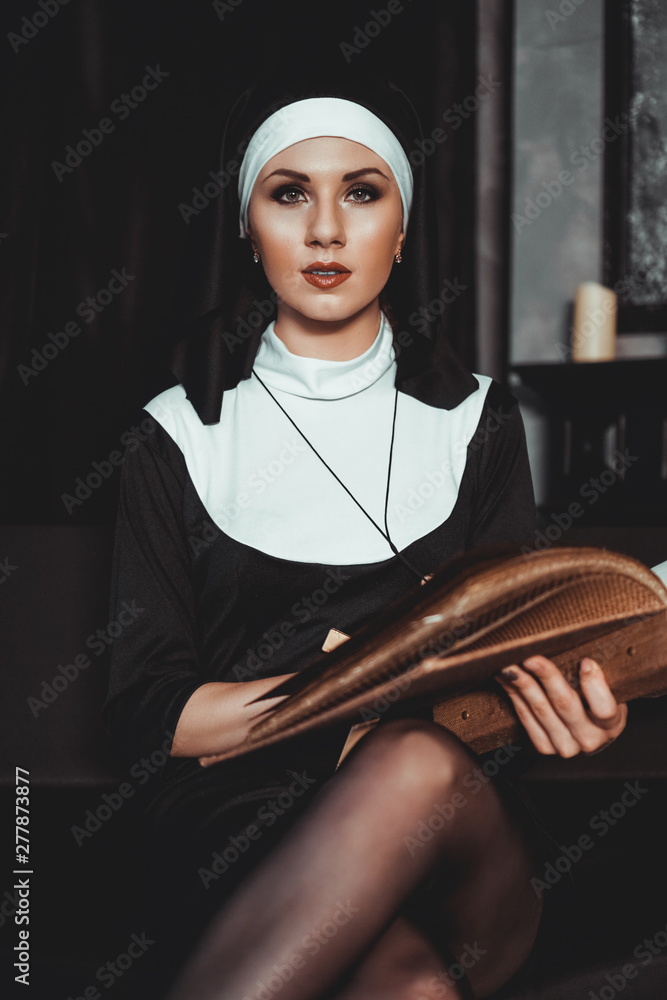 Beautiful young nun in religion black suit holds Bible and posing on ...
