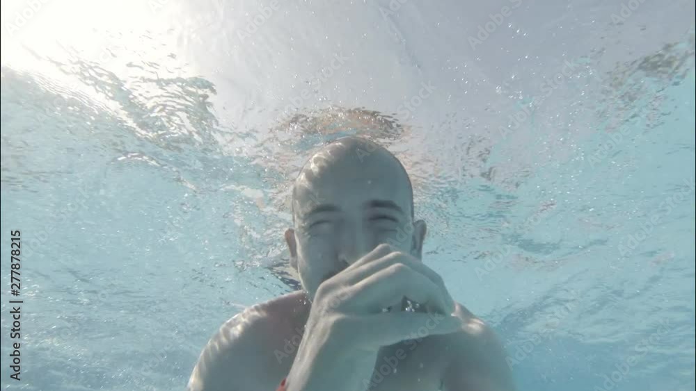 Man holding his nose jumping into the pool and swims under water. vídeo ...