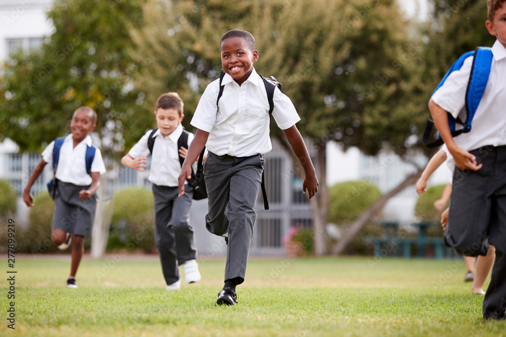 Excited Elementary School Pupils Wearing Uniform Running Across Field ...