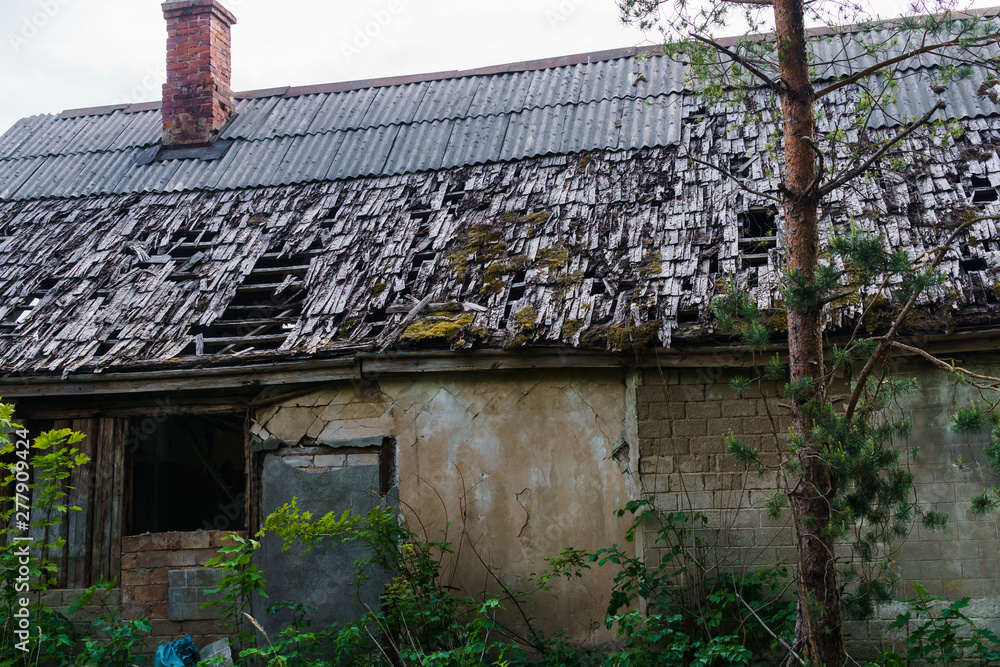 Abandoned, falling apart house in the countryside. Holes in the roof ...