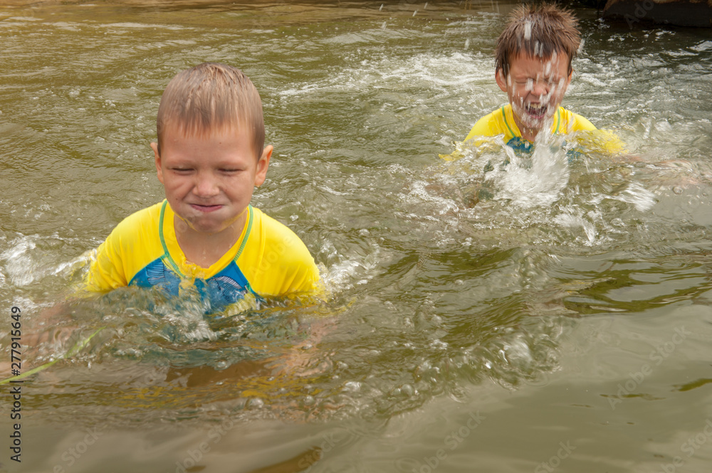 Funny children in swimsuits accelerate on wooden bridge near river and ...