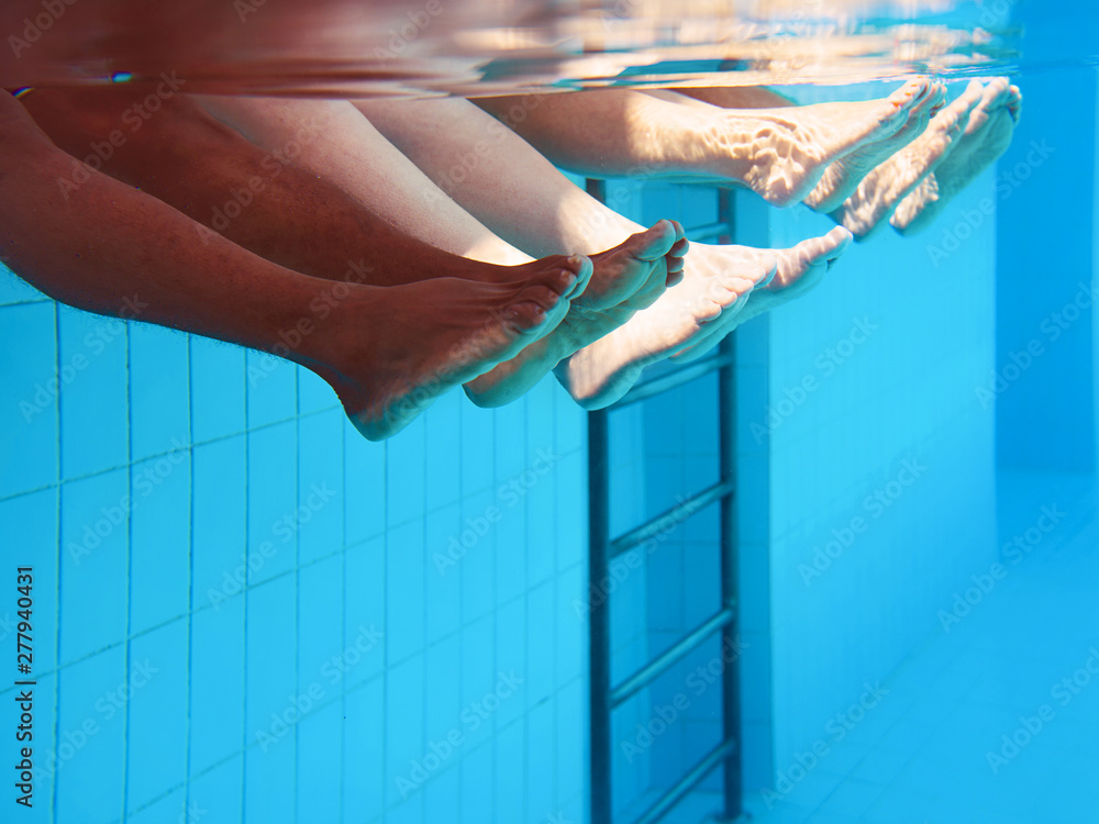 four people legs underwater in the swimming pool. Party. Summer ...