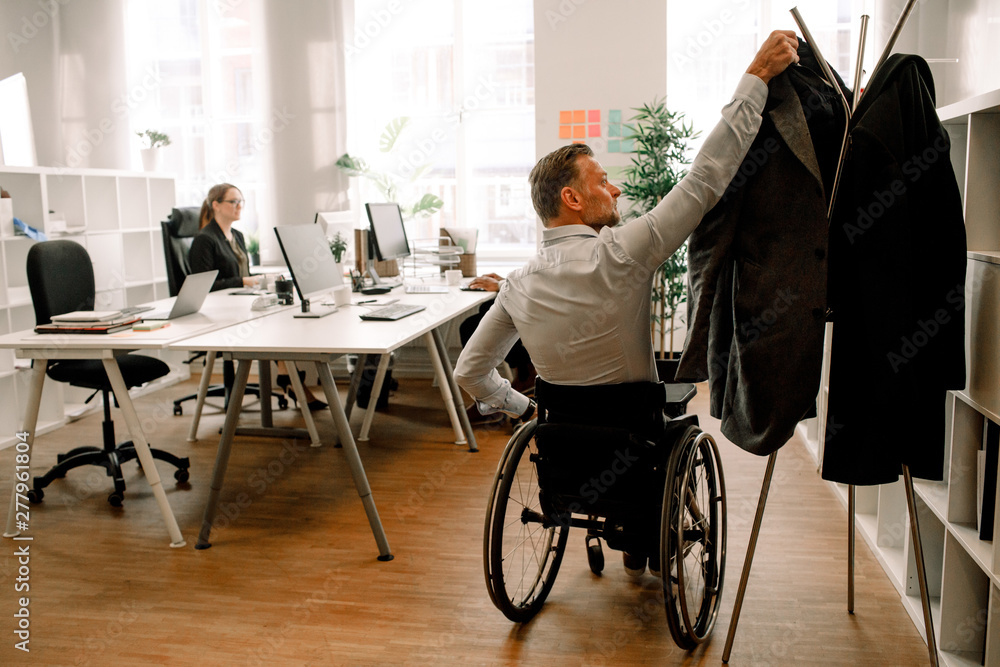 Businessman hanging coat in office Stock Photo | Adobe Stock
