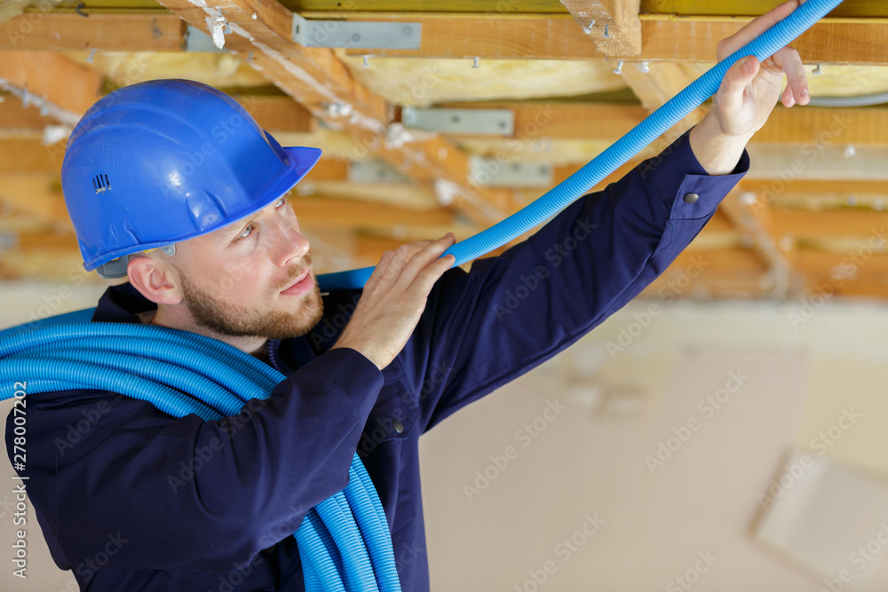 builder installing blue ducting between roof joists Stock Photo | Adobe ...