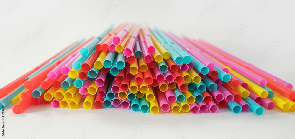 Colorful single-use plastic drinking straws spread on a white ...