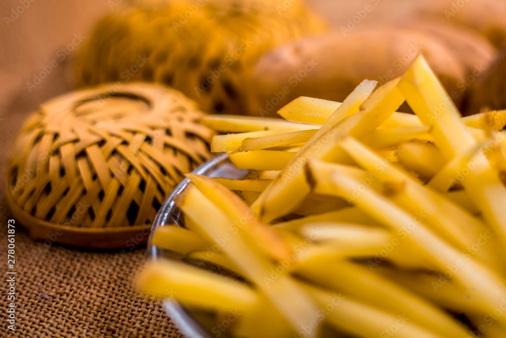 Raw cut french fries in a transparent glass plate along with raw potato ...