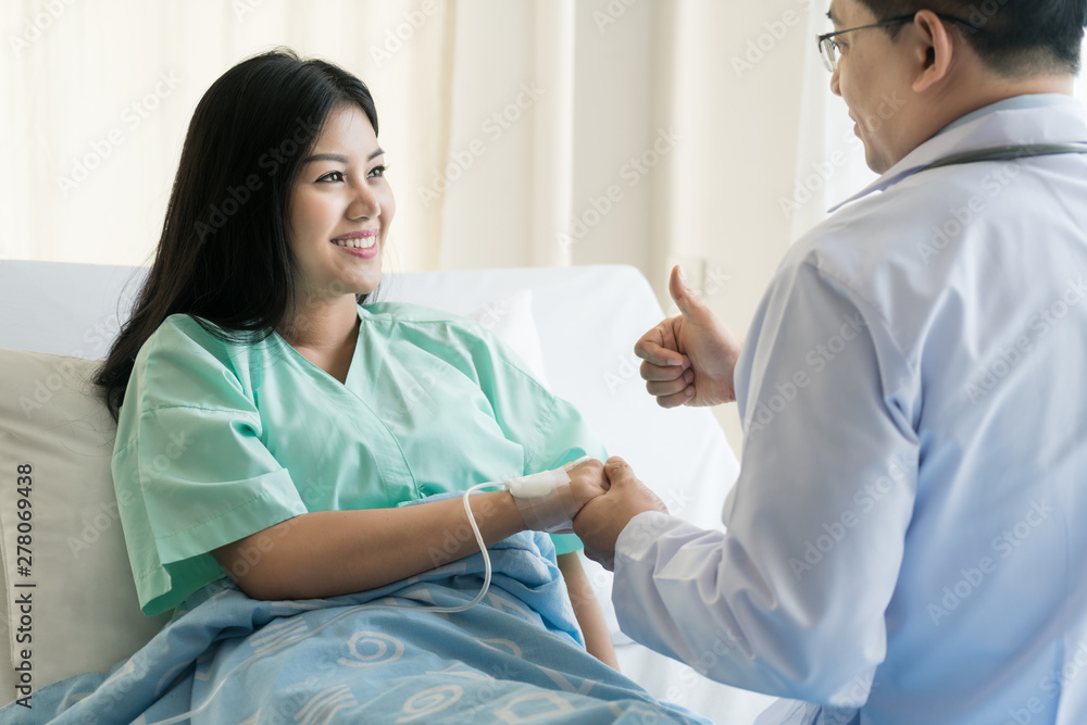 Hand of man doctor reassuring his female patient with thump up in bed ...