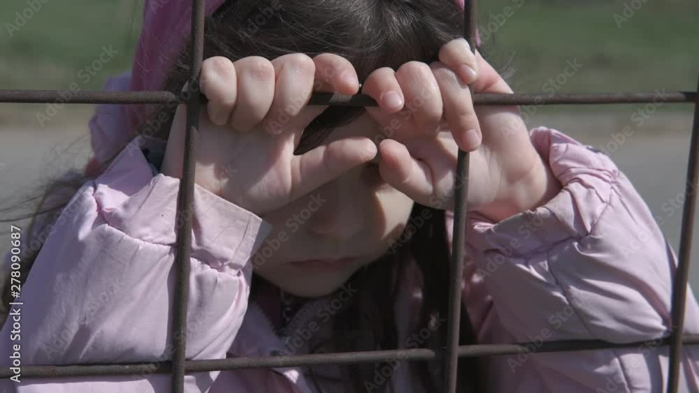 Refugee in childhood. Children in a cage. Sad little girl behind an ...