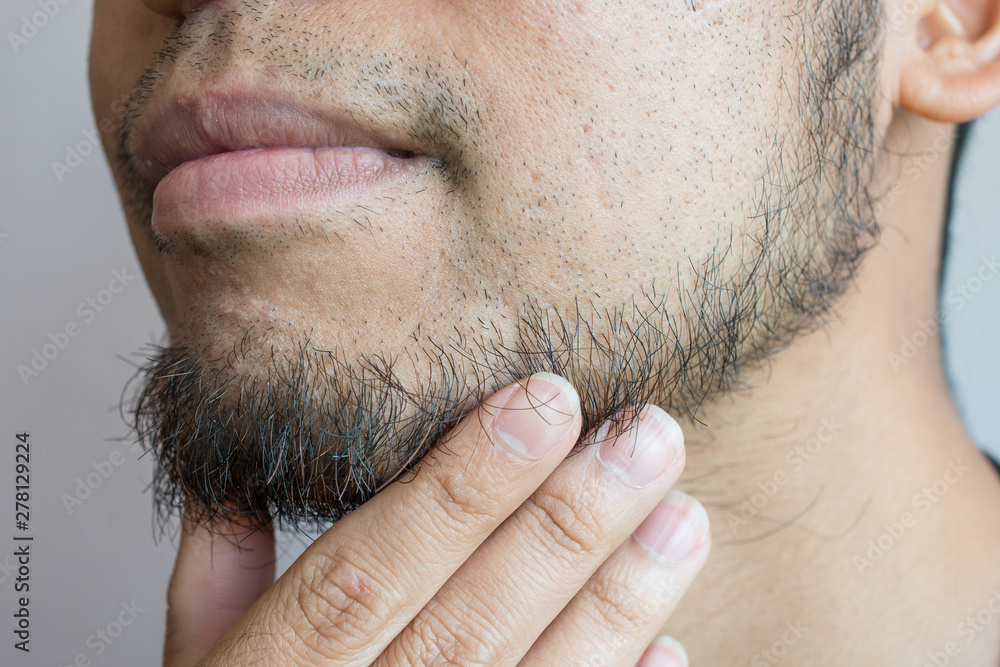 Cropped shot of Asian man touching his beard grows on a part of lower ...