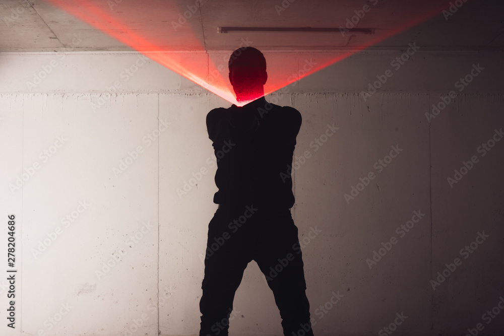 Silhouette of an armed man holding his gun and pointing with his laser ...