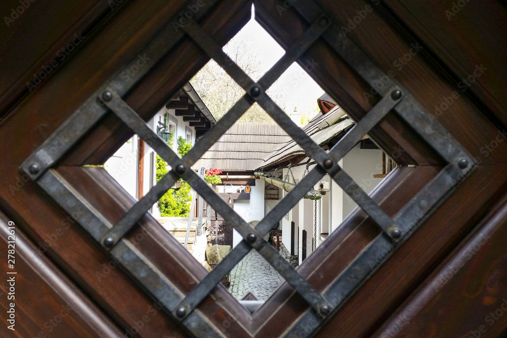 View of cozy old courtyard through rhombus window with cells in gate ...