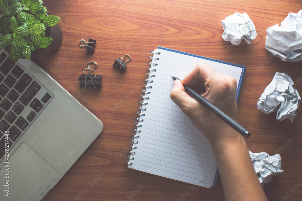 Woman hand is writing a pen. On a wooden office table Composed of ...
