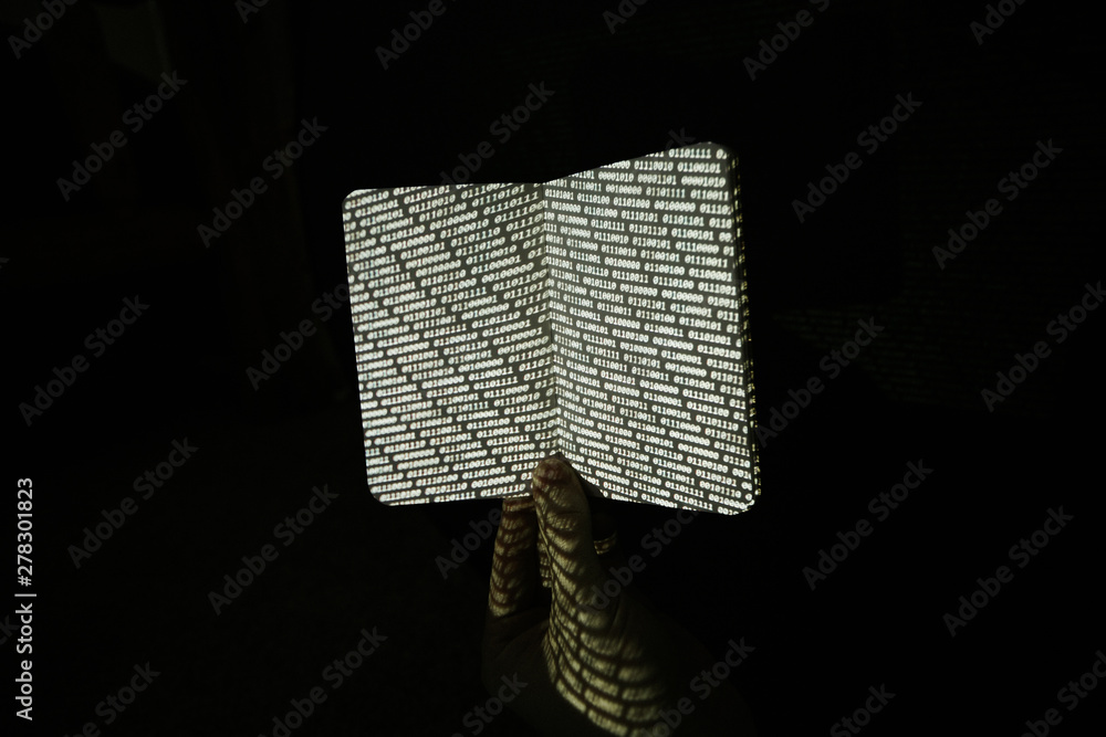 Binary Code projected onto physical notepad. Stock Photo | Adobe Stock