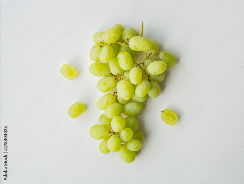 A top-down shot of a bunch of green grapes on a plain white background ...