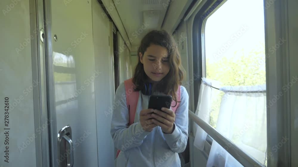 teen girl walks on a train compartment car with a backpack and a ...