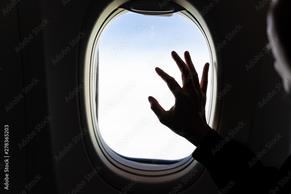 Hand on airplane window with aerial view of white clouds with ...