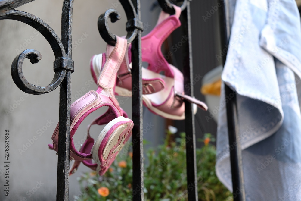 Scarpe da bambina appese ad asciugare su una ringhiera di ferro in un ...