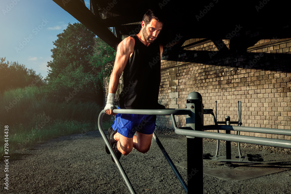 boxer athlete in outdoor training doing pushups at the dip station ...